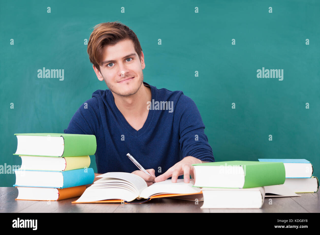 Serious Male Student Surrounded With Stack Of Books Stock Photo - Alamy