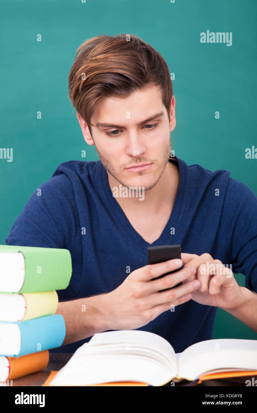 Portrait Of Male Student Using Cellphone While Studying Stock Photo - Alamy