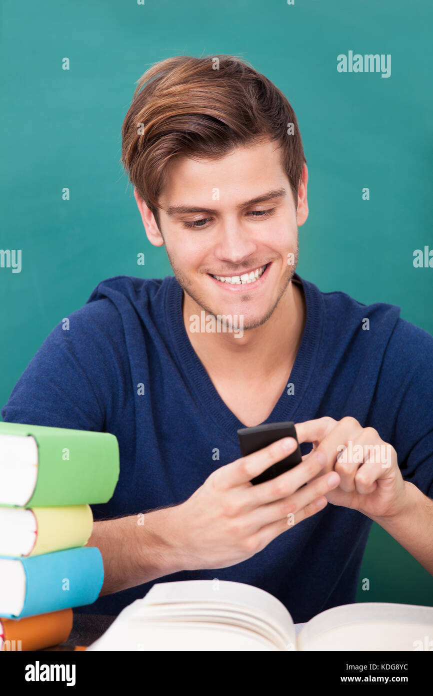 Happy Male Student Using Cellphone While Studying Stock Photo - Alamy