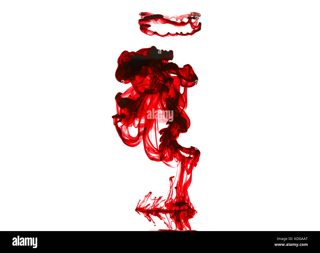 Red color drop in water photographed in motion. Cloud of red ink in ...