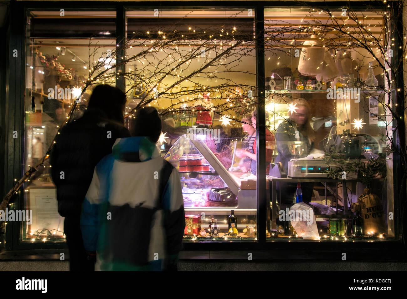 Two persons looking into the window of a delicatessen shop during ...