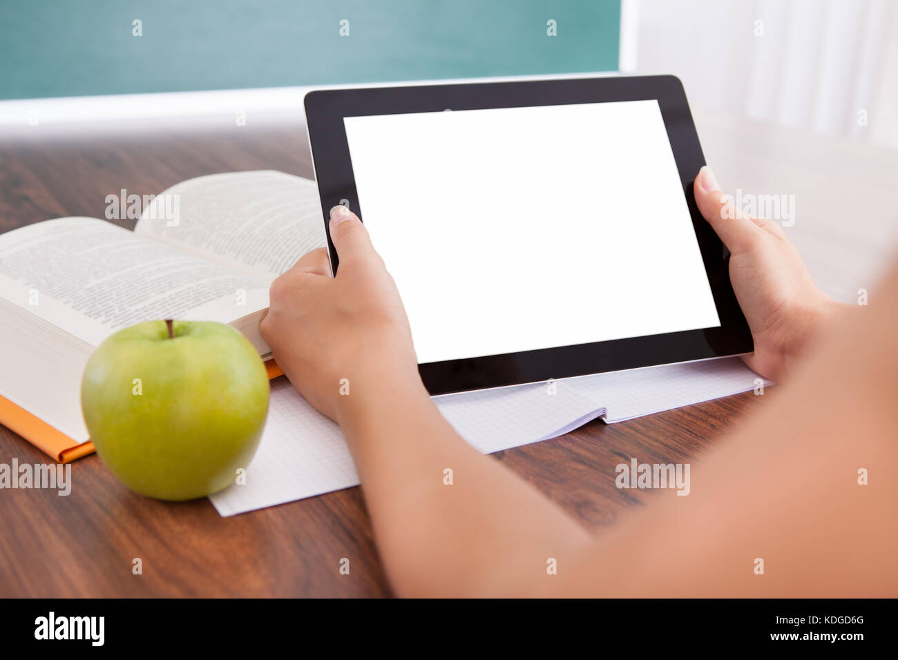 Student with apple and book on desk holding digital tablet Stock Photo ...