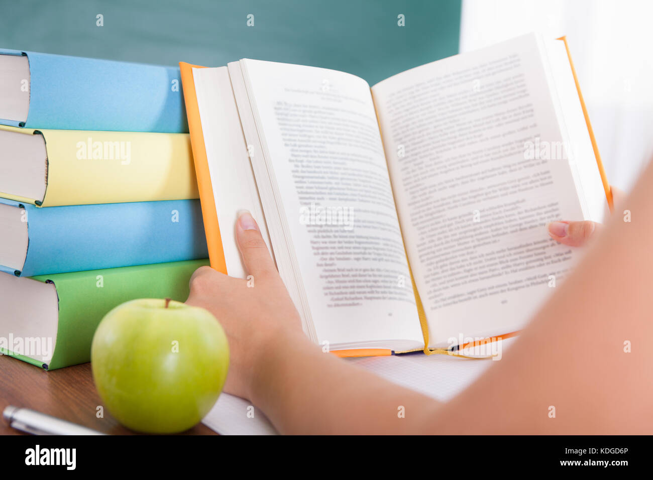 Female student studying with stack of books and green apple Stock Photo ...