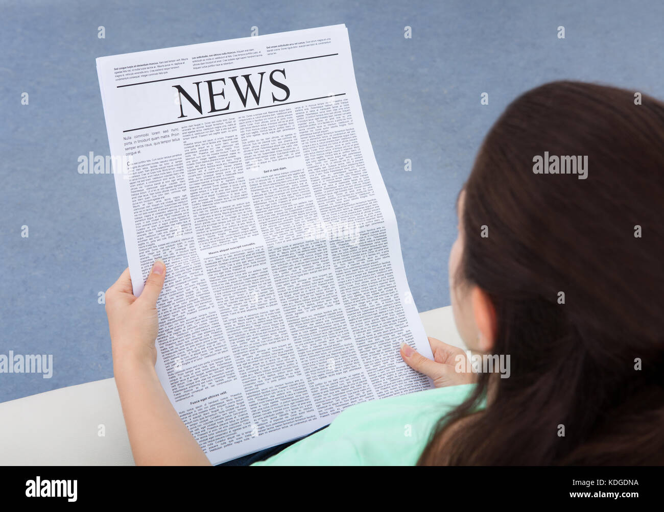 Rear View Of A Woman Sitting On Couch Reading Newspaper Stock Photo - Alamy