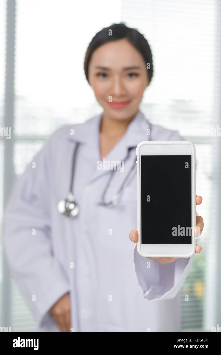 A beautiful smiling woman doctor with a stethoscope showing smartphone ...