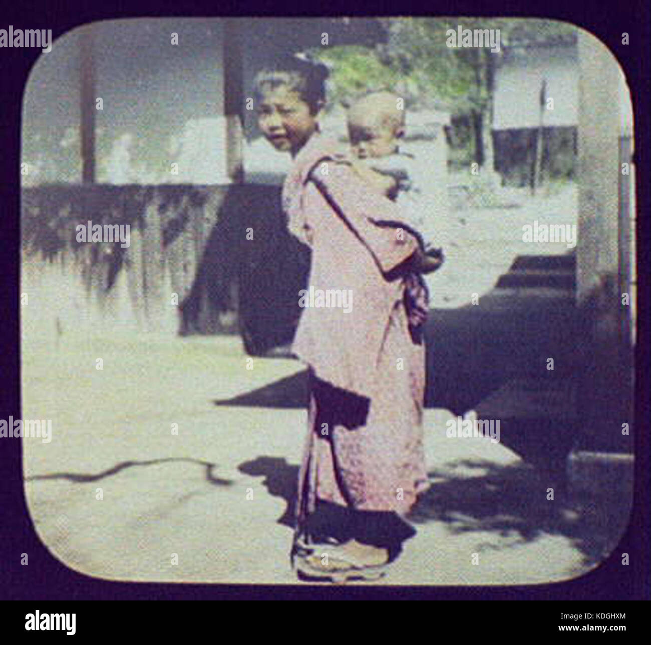 This photograph captures a mother carrying her baby on her back, a ...