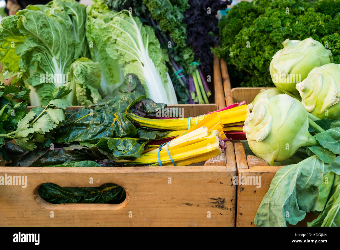 Assorted fresh green vegetables in boxes at a farmers market after ...