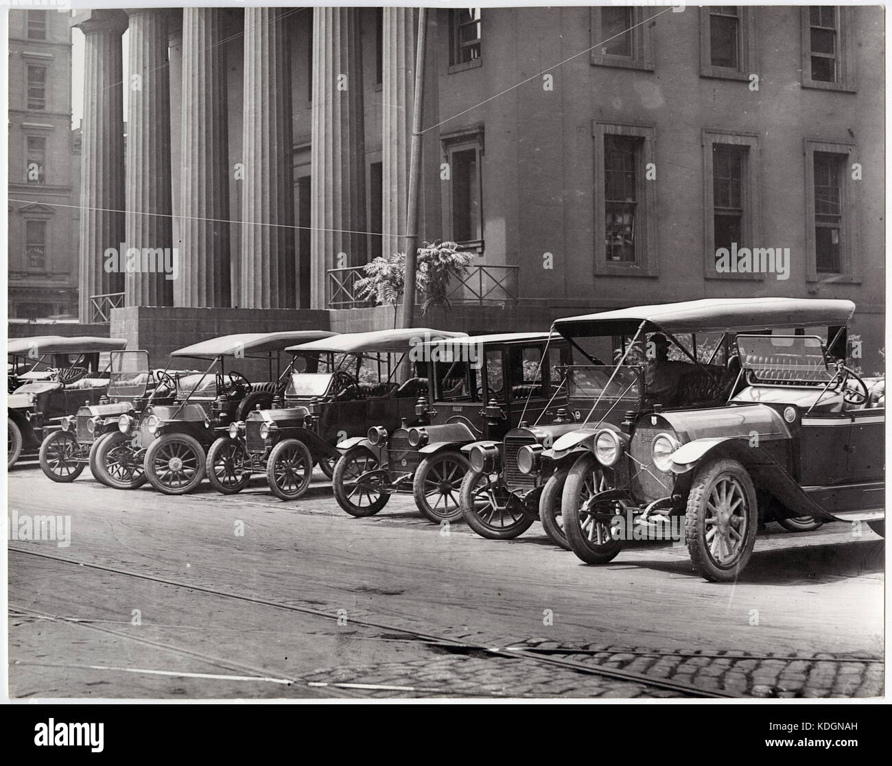 Row of cars parked in front of an unidentified building with large ...