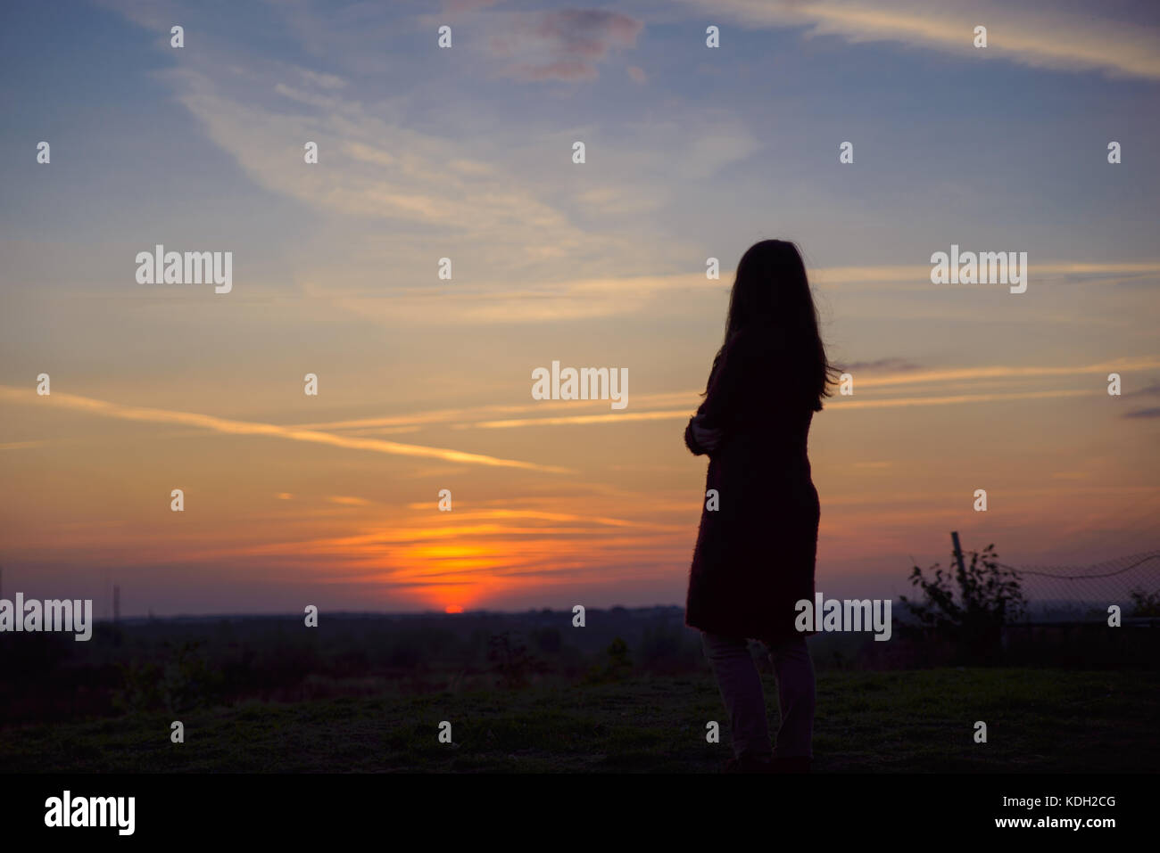 Silhouette of a young woman standing on sunset Stock Photo - Alamy