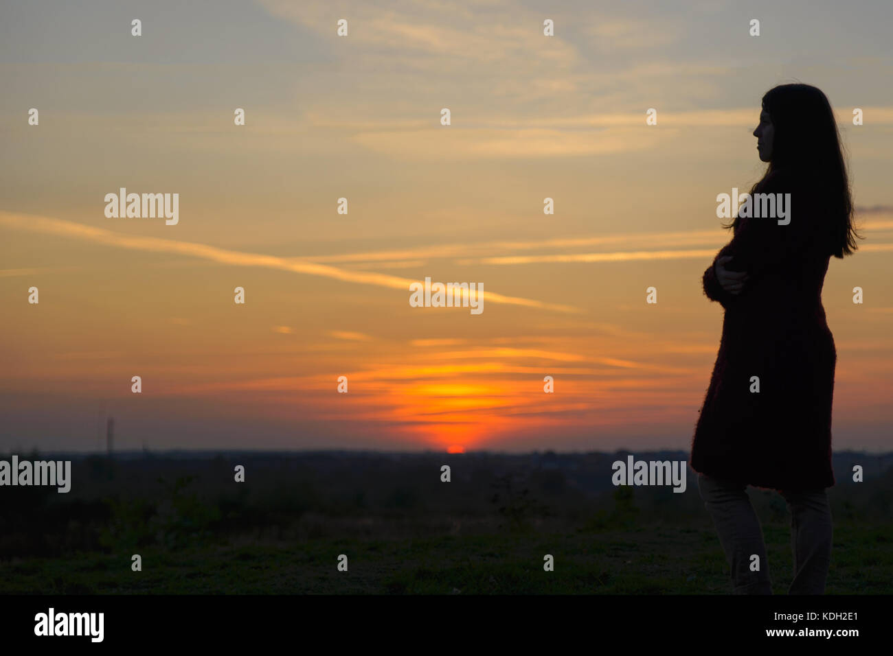 Silhouette of a young woman standing on sunset Stock Photo - Alamy