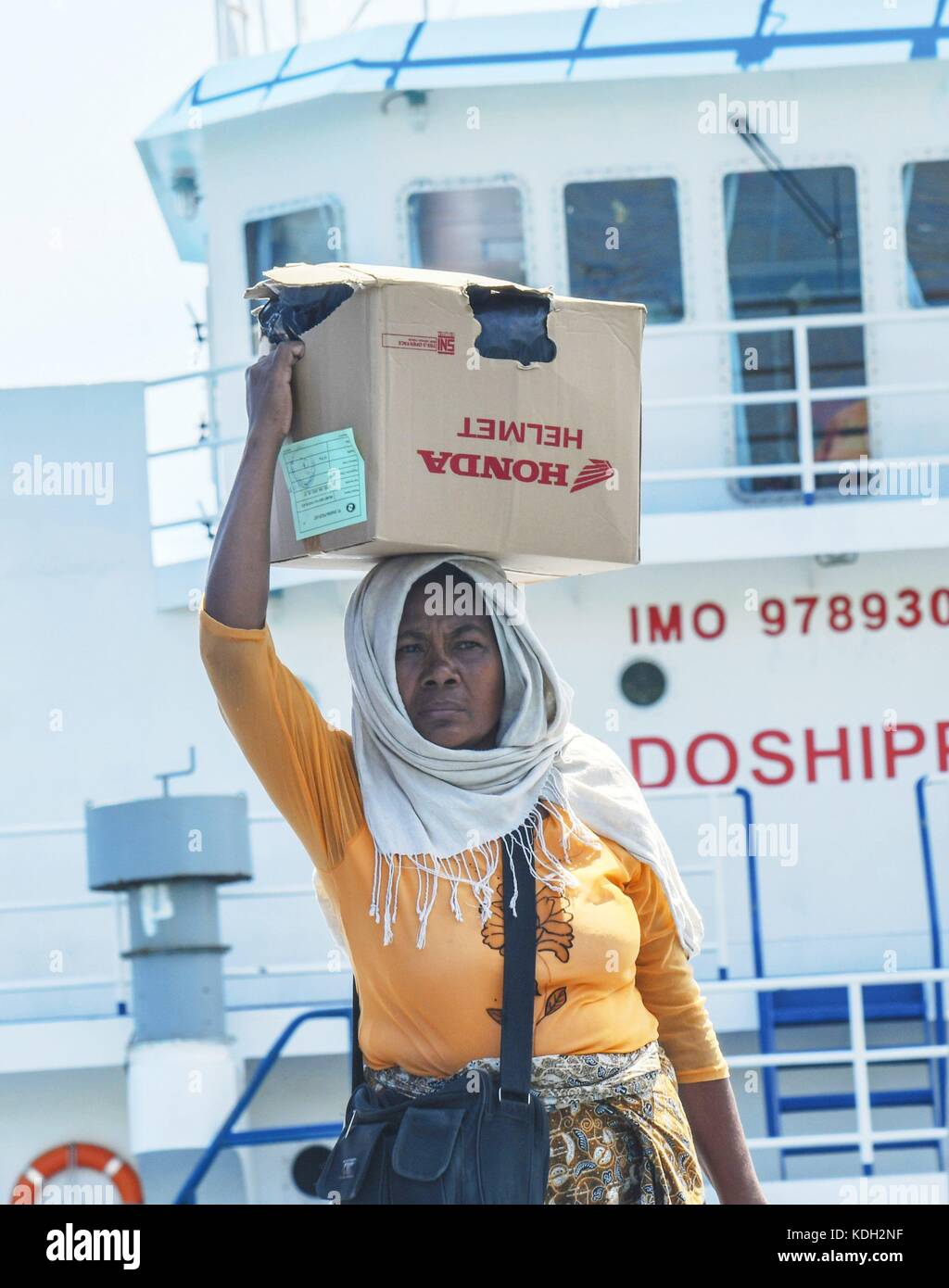 Woman carrying goods on her head when leaving a ferry, Atauro, Timor ...