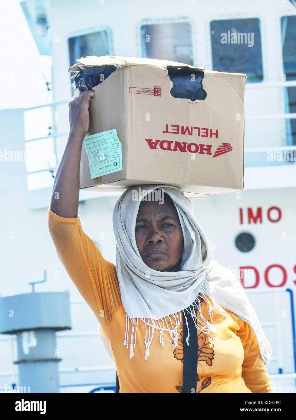 Woman carrying goods on her head when leaving a ferry, Atauro, Timor ...