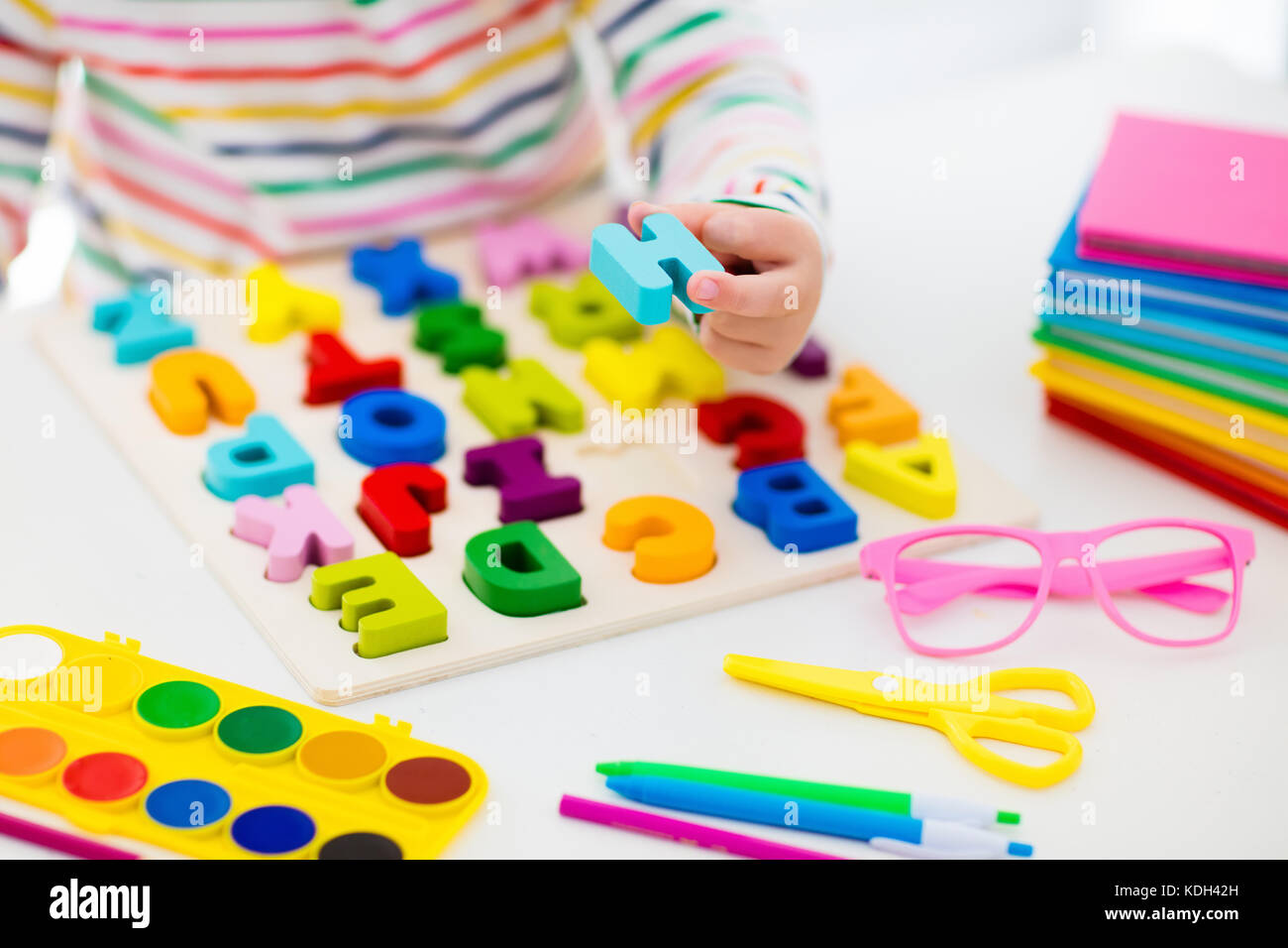 Child doing homework for school at white desk. Wooden educational abc ...
