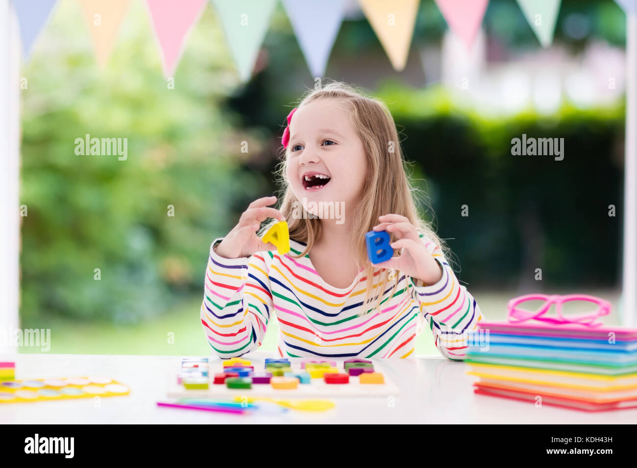 Child doing homework for school at white desk. Wooden educational abc ...