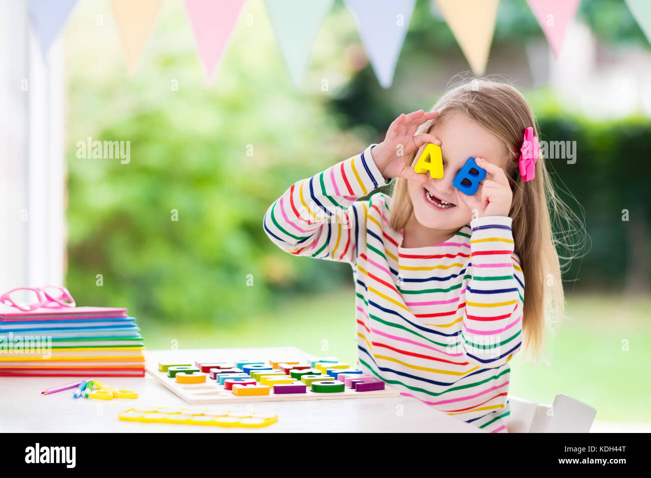 Child doing homework for school at white desk. Wooden educational abc ...