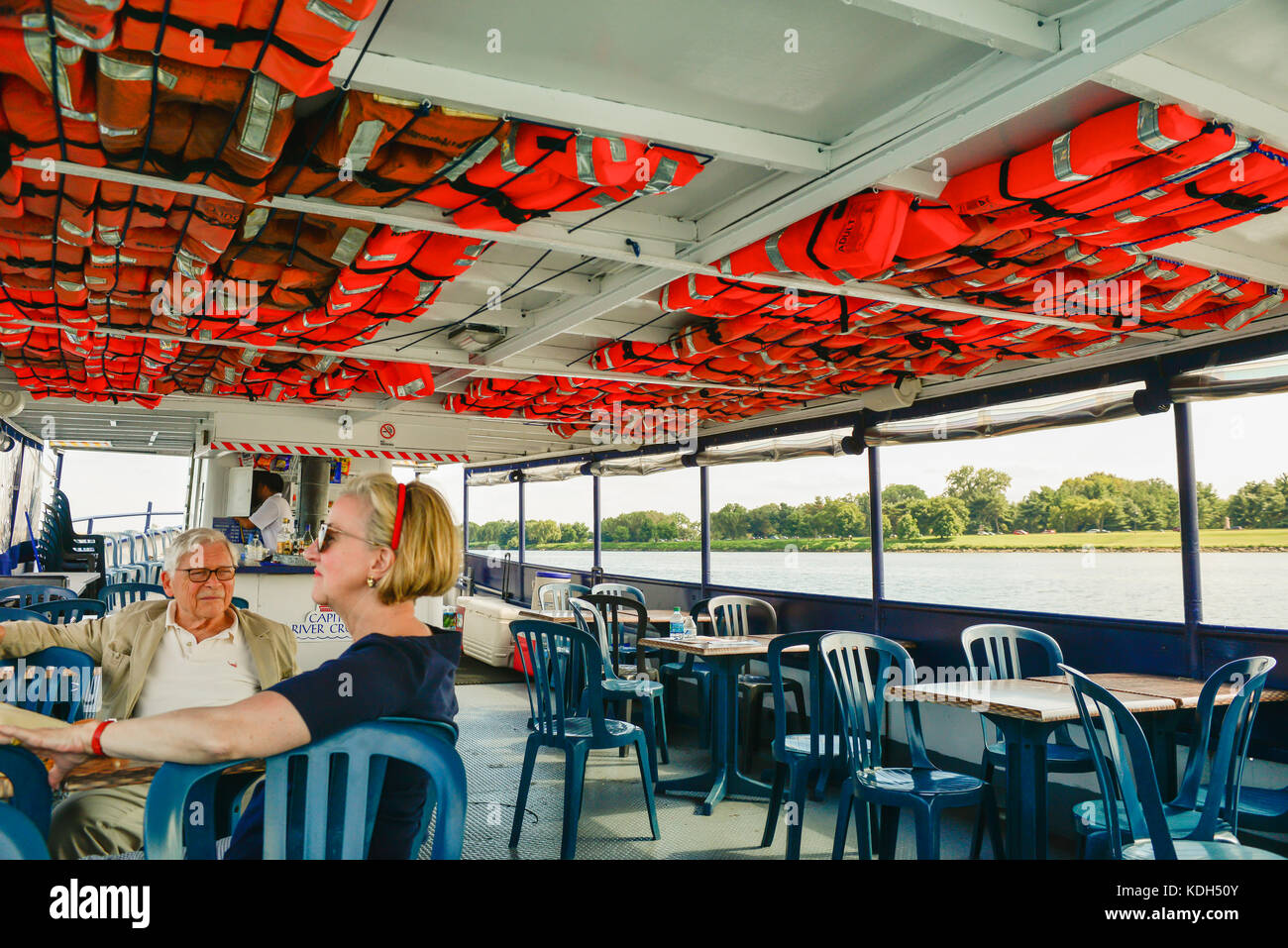 A couple of sightseers relax along the semi-open tour boat cruising on ...