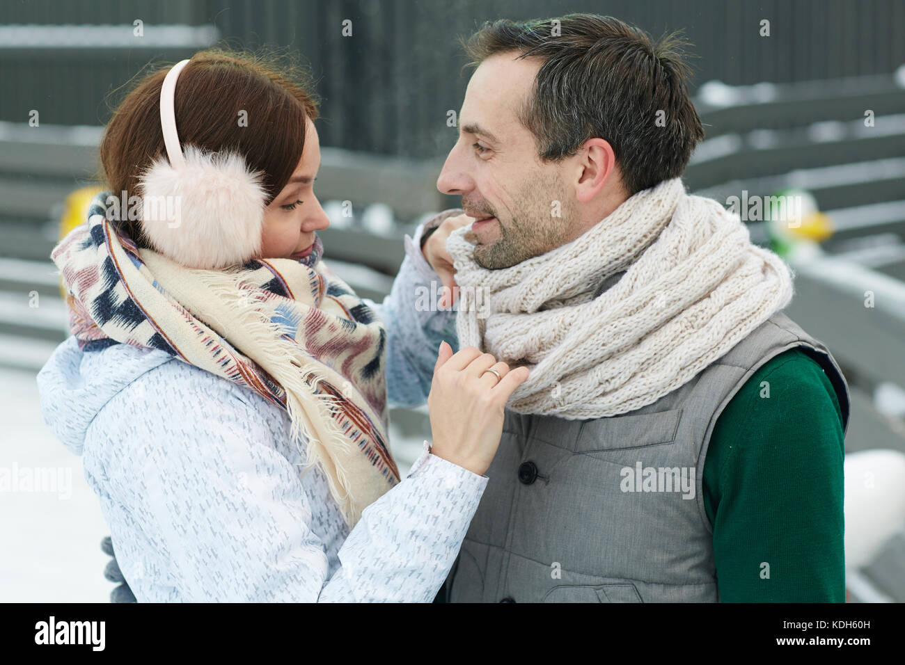 Amorous female touching knitted scarf of her sweetheart outdoors Stock ...