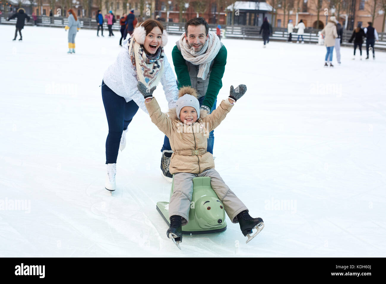Ecstatic little girl enjoying riding on toy while parents pushing it on ...