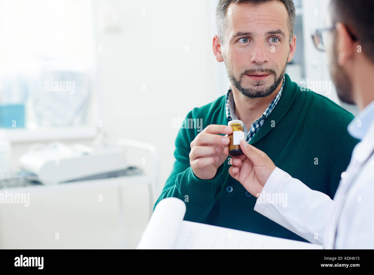 Sick man taking bottle with medication offered by his doctor in ...