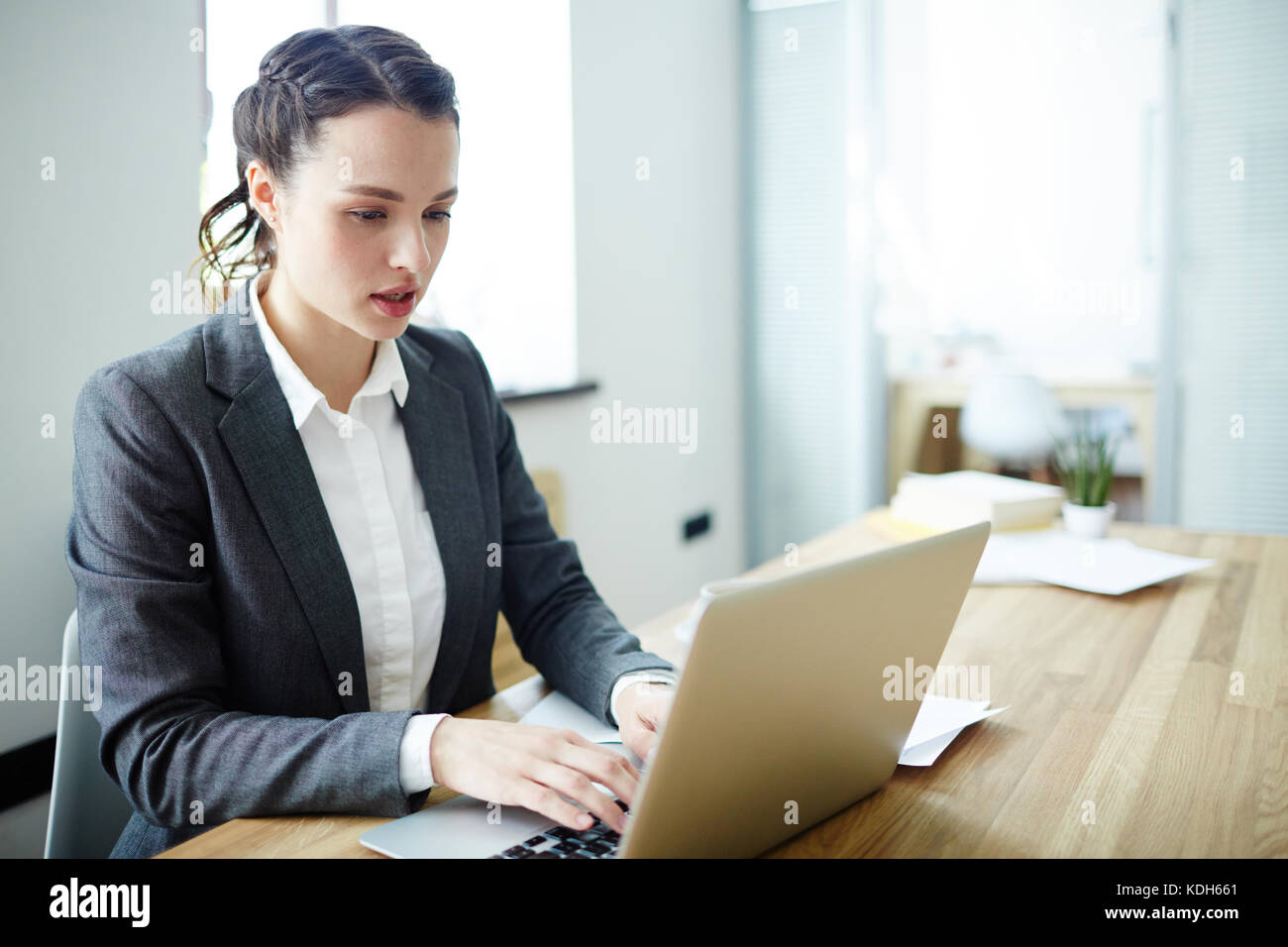 Young office worker sitting in front of laptop and entering information ...