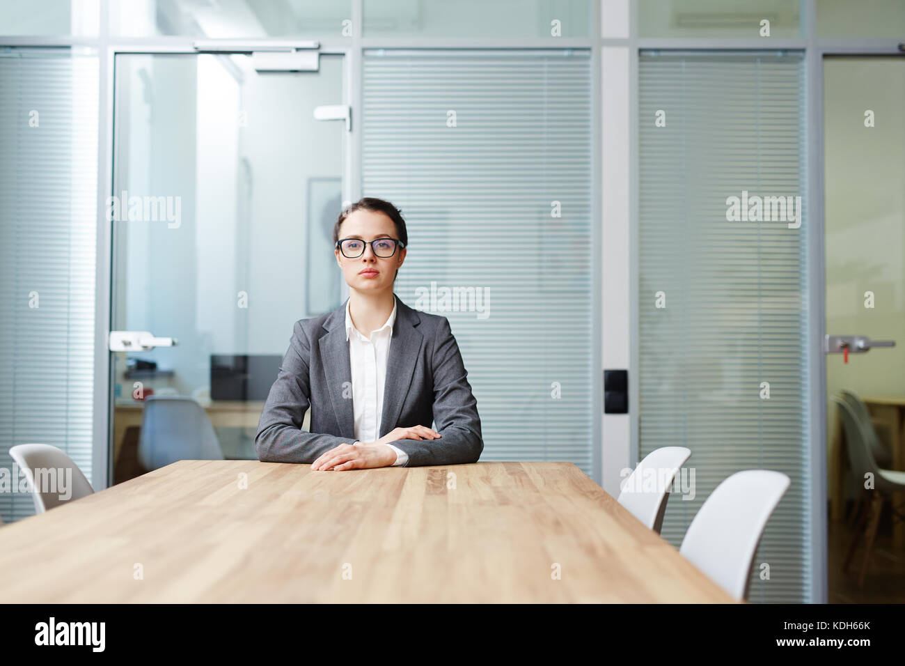 Serious employer waiting for another applicant by table in boardroom ...