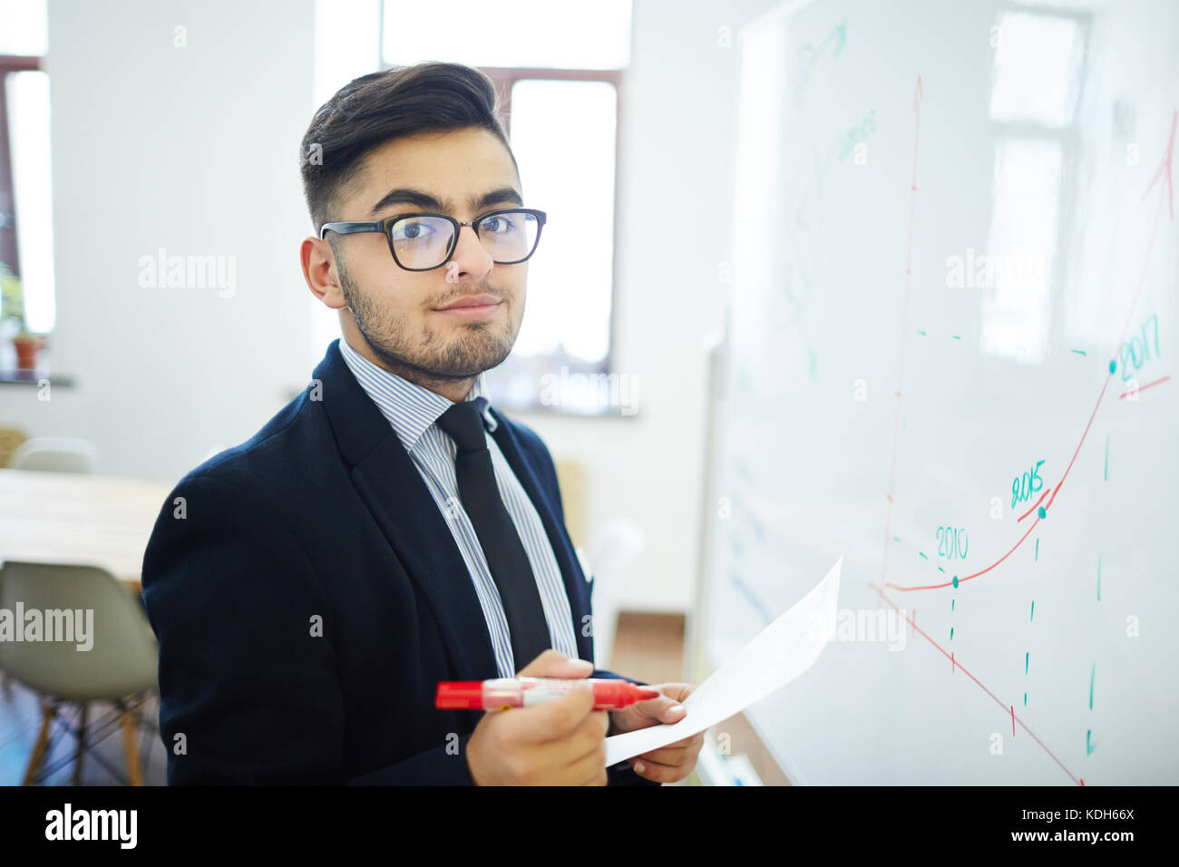 Businessman with red highlighter and paper standing by whiteboard with ...