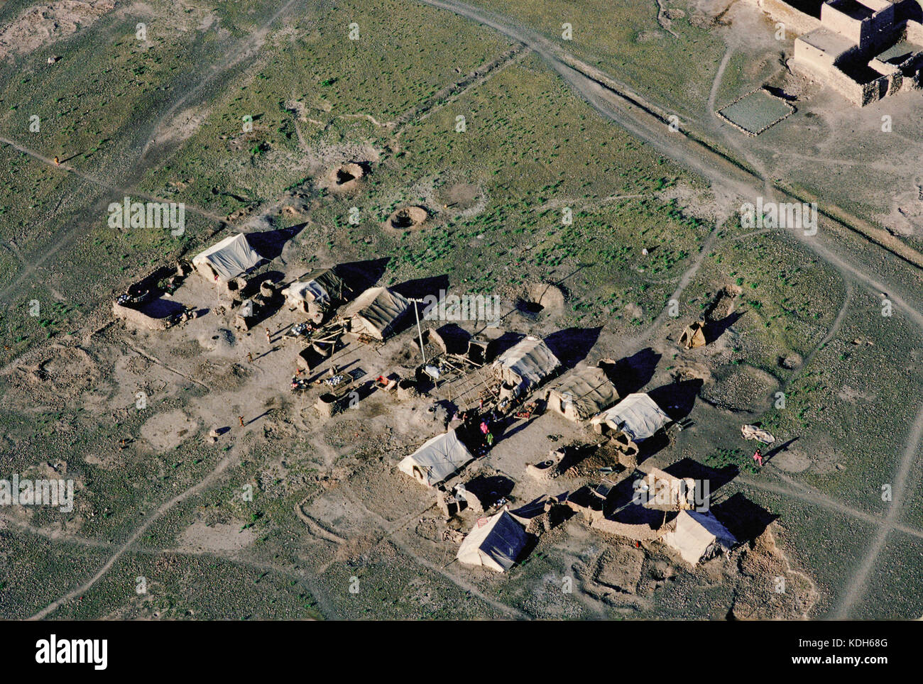 Aerial view of a rural settlement with tents and structures on barren ...