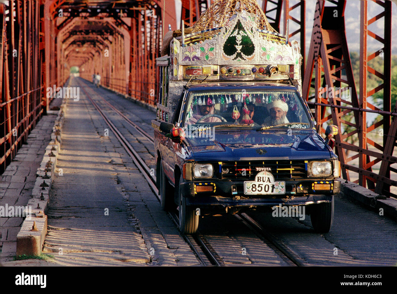 A decorated Toyota taxi crosses the railway bridge at Kalabagh ...