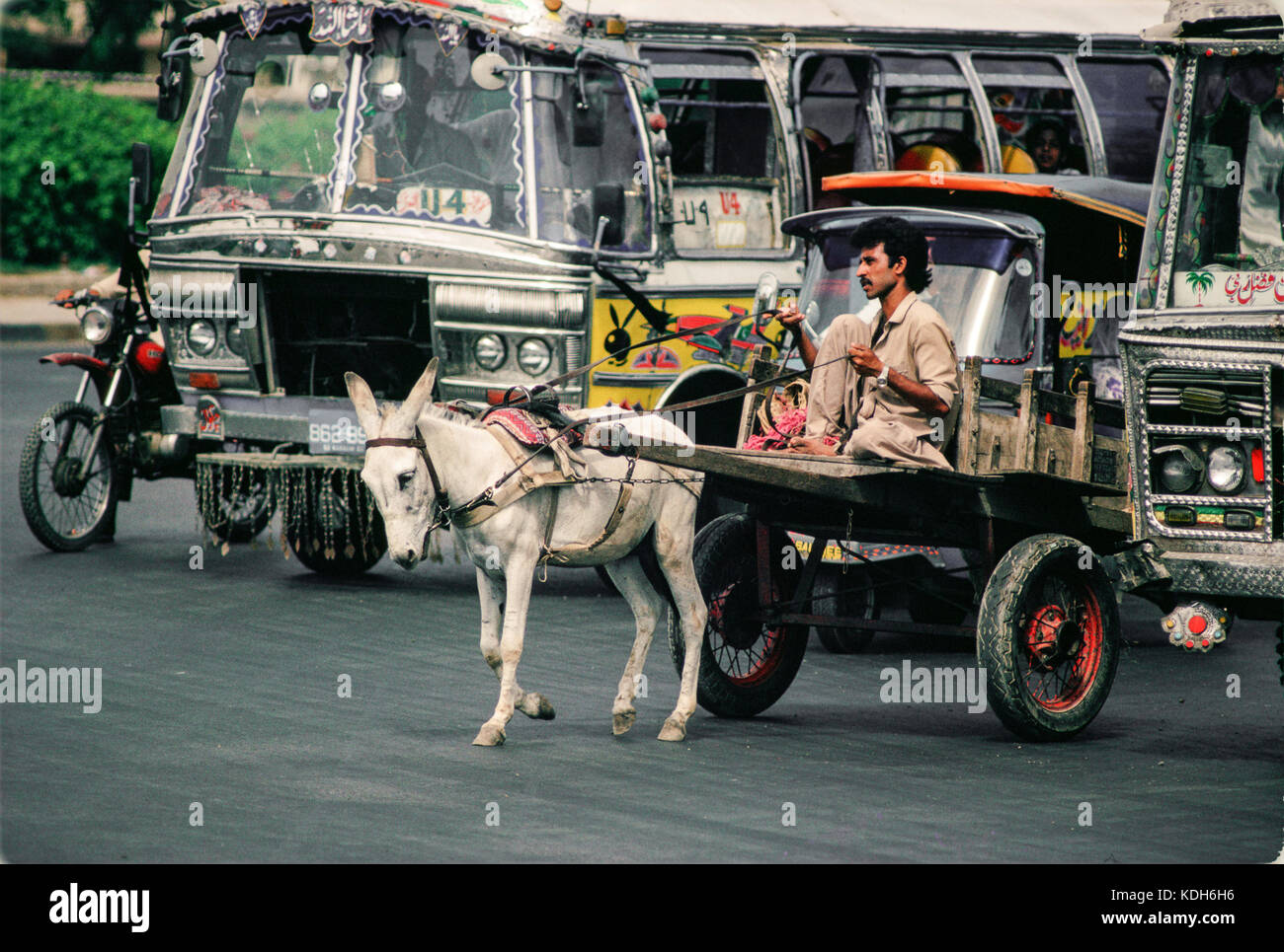 Traffic scene in Karachi featuring buses, a motorcycle, and a donkey ...