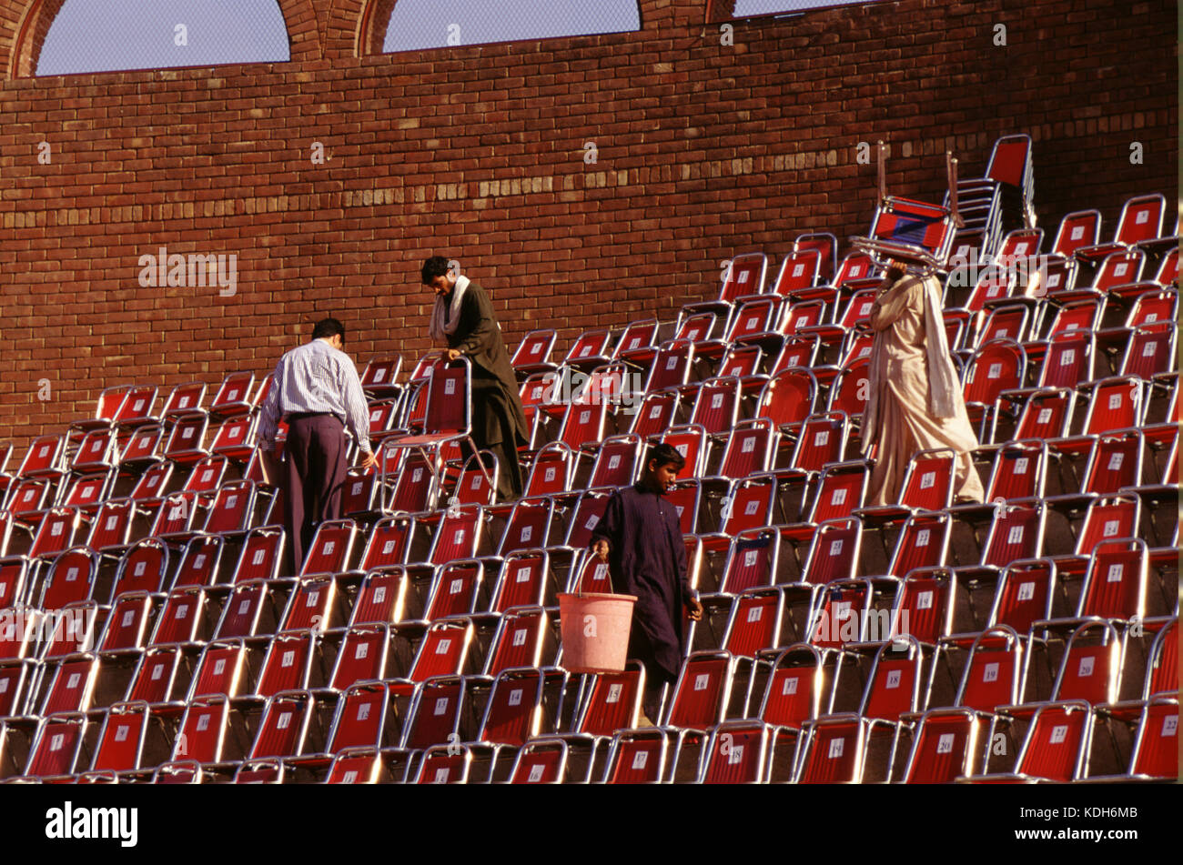 Workers arrange red chairs in a seating area at an outdoor theatre ...