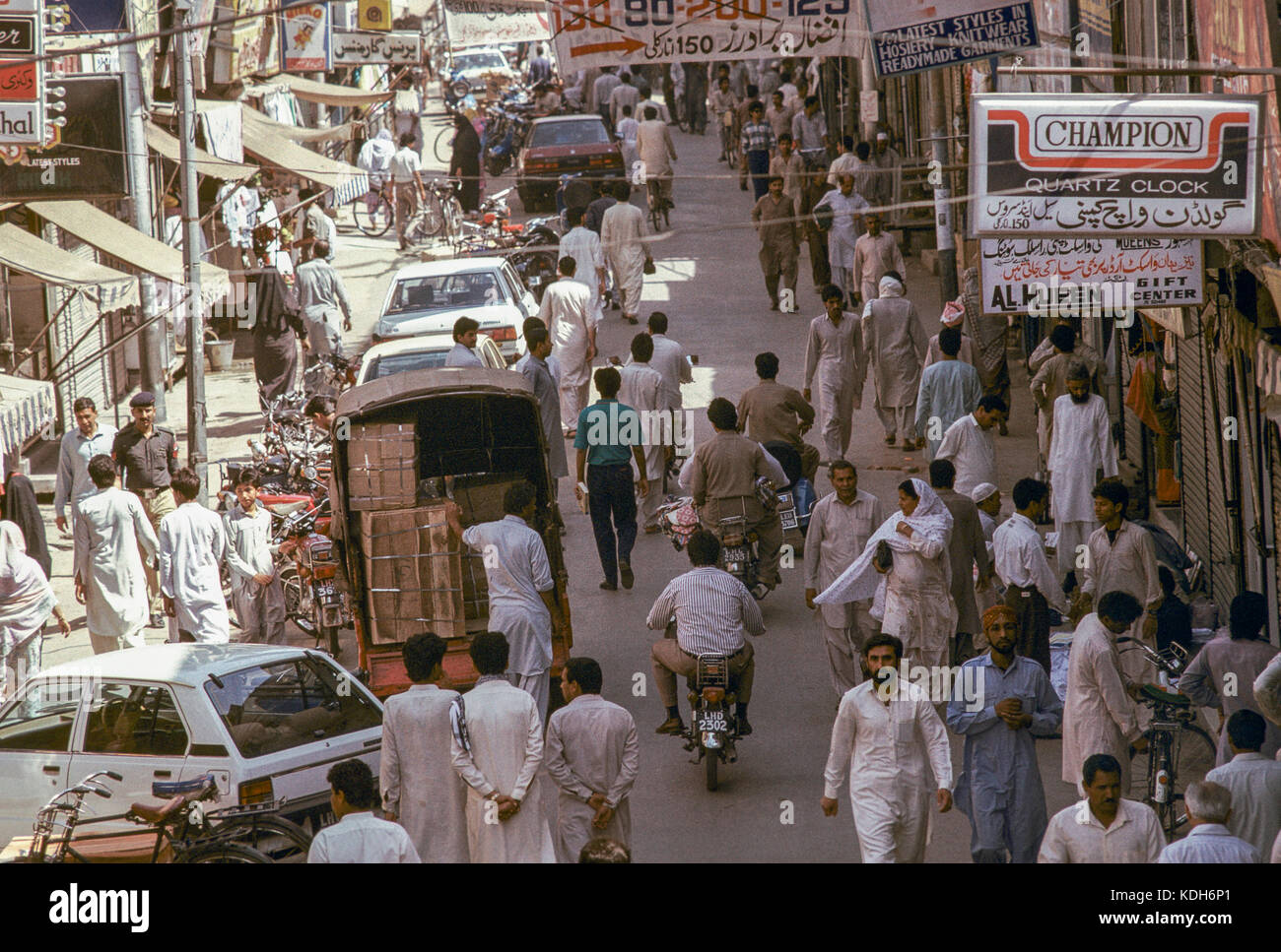 A bustling street scene in Pakistan, with people, vehicles, and shop ...