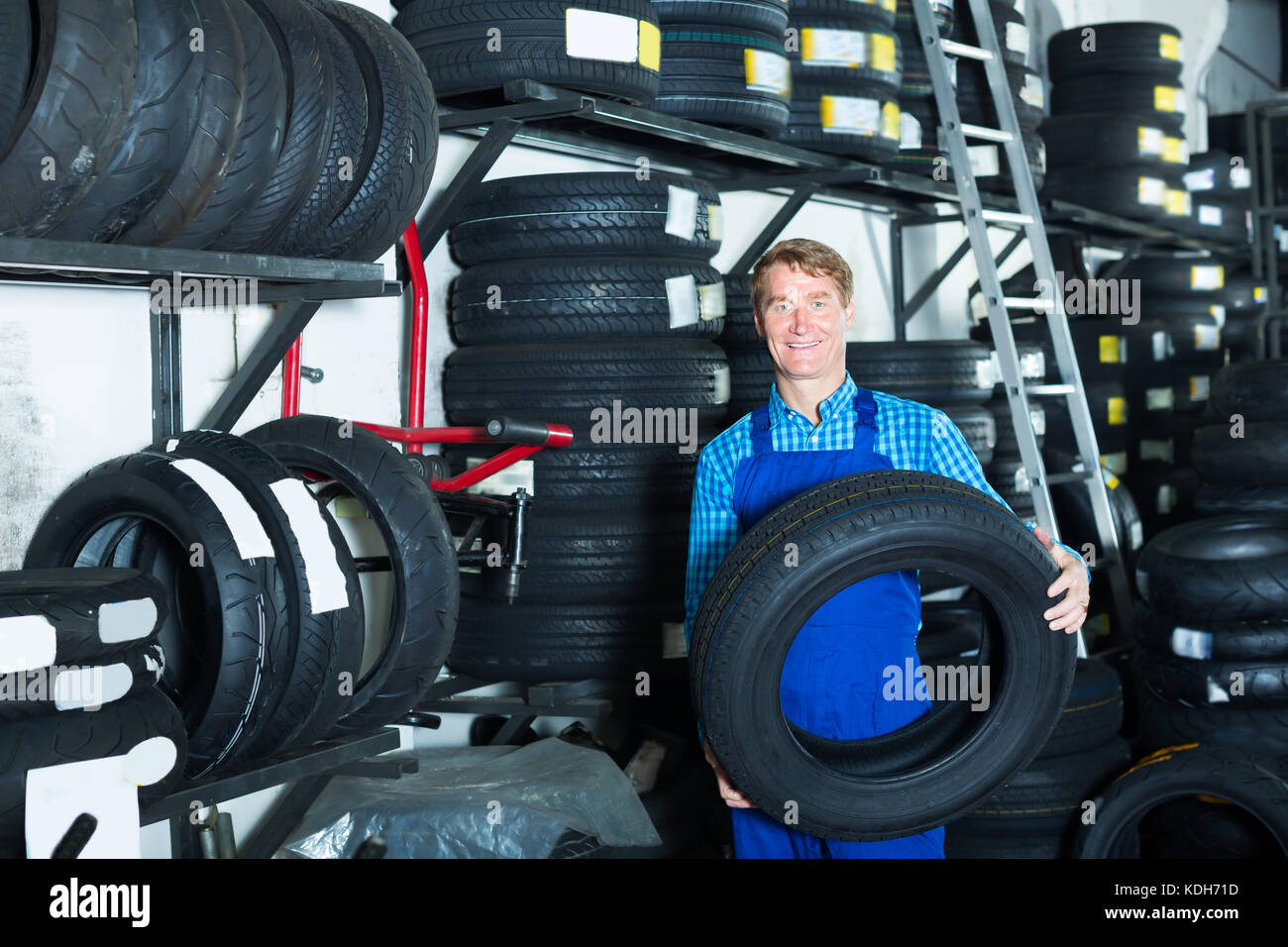 Mature mechanic man standing with new car tires in hands in shop Stock Photo - Alamy