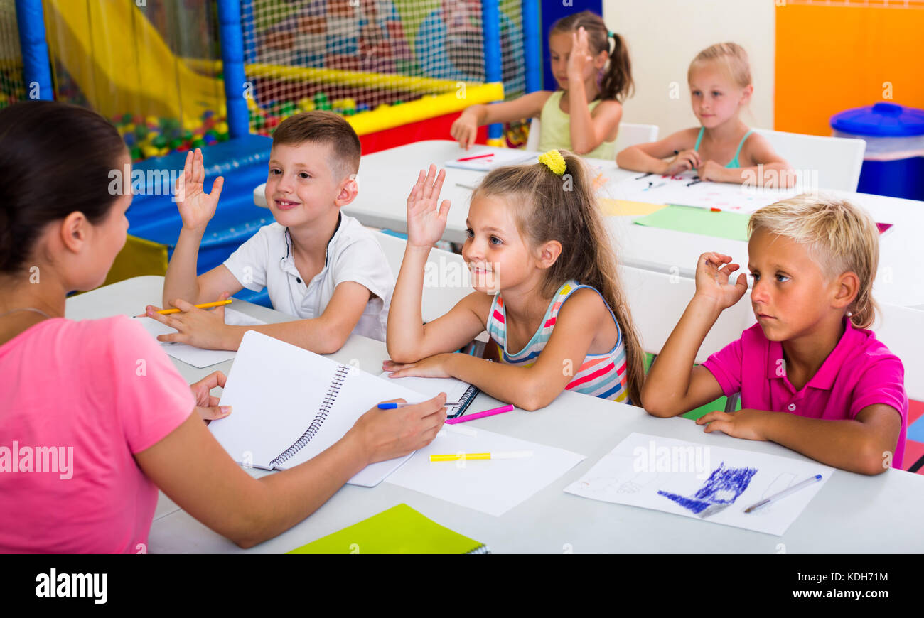 primary school kids sitting at school class and listening to a teacher ...