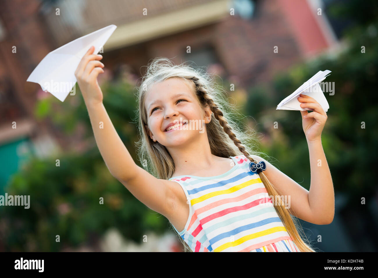happy girl throwing simple paper airplane toy in air on sunny day Stock ...