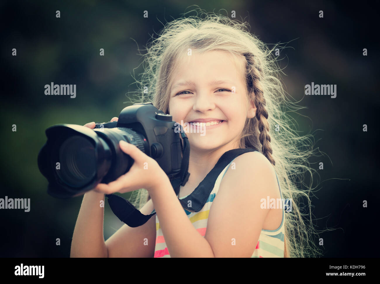 positive female child taking pictures with camera in park on summer day ...