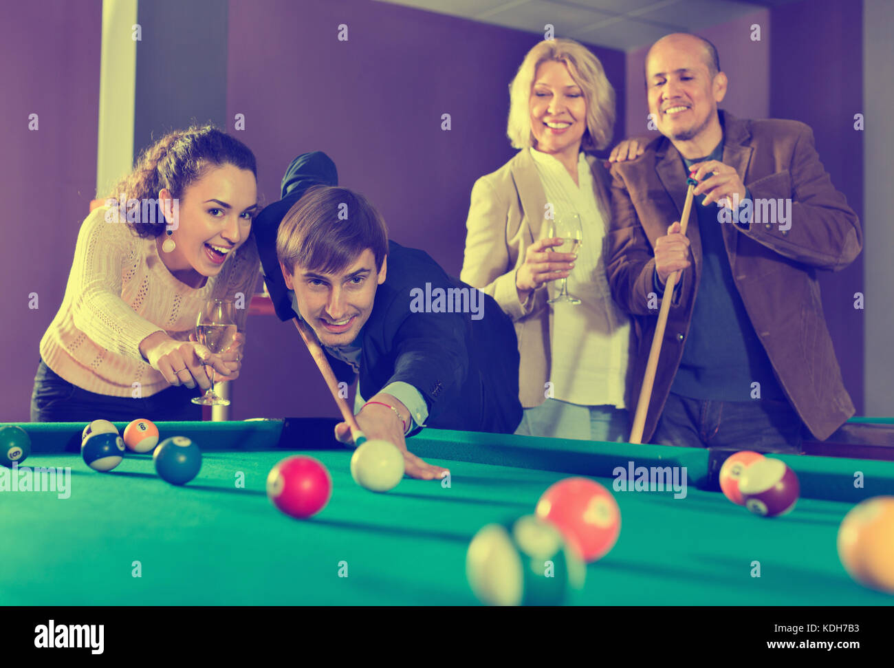 Group of positive friends playing billiards and smiling in night club ...