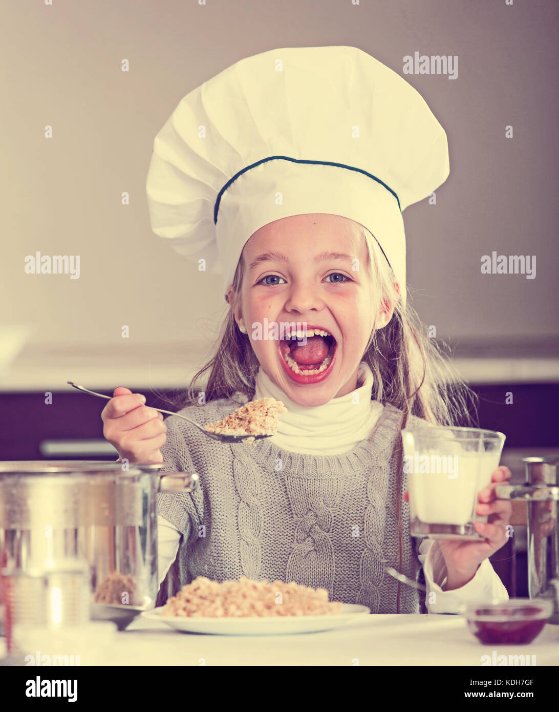 Little girl in cook hat with milk and oatmil kasha Stock Photo - Alamy