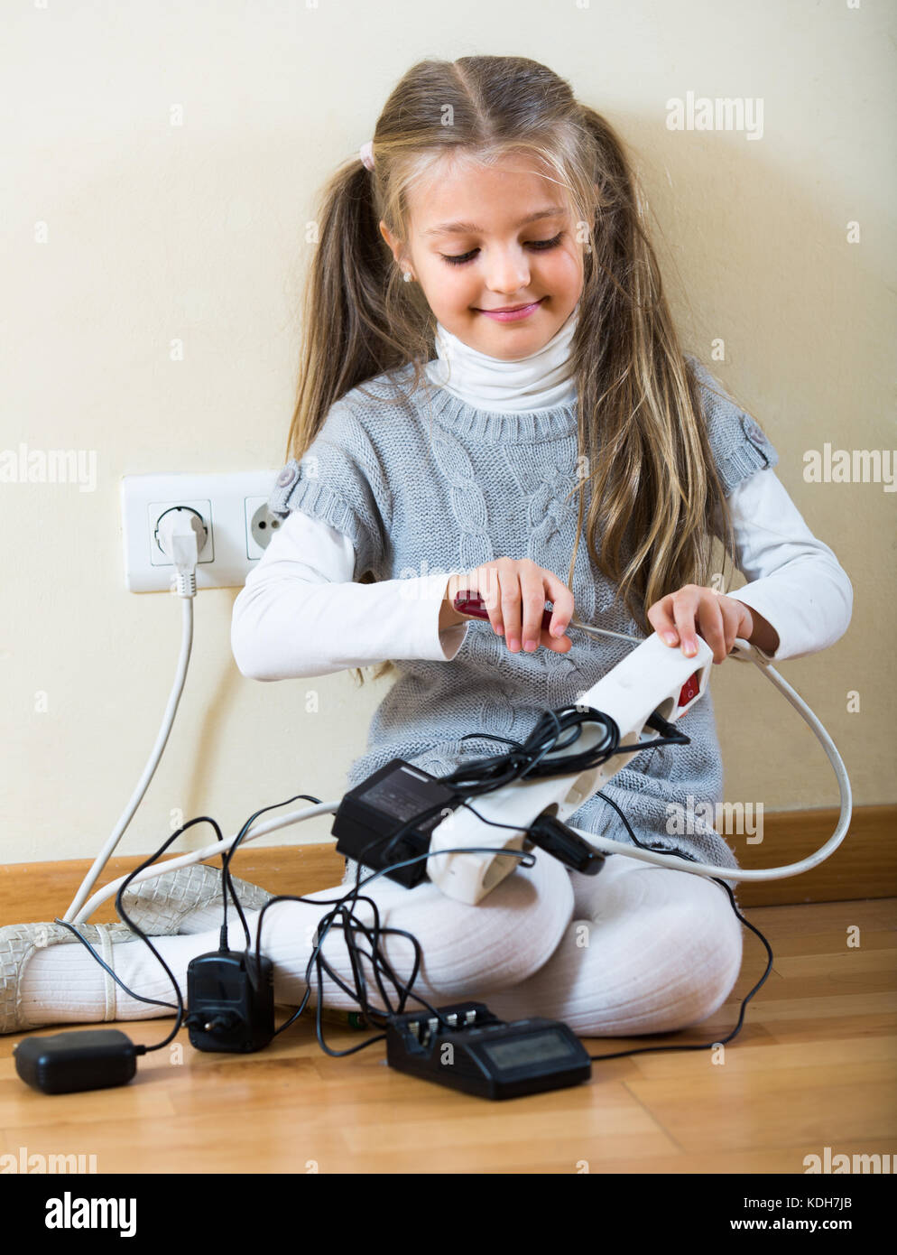 Smiling little girl dangerously playing with sockets and electricity ...