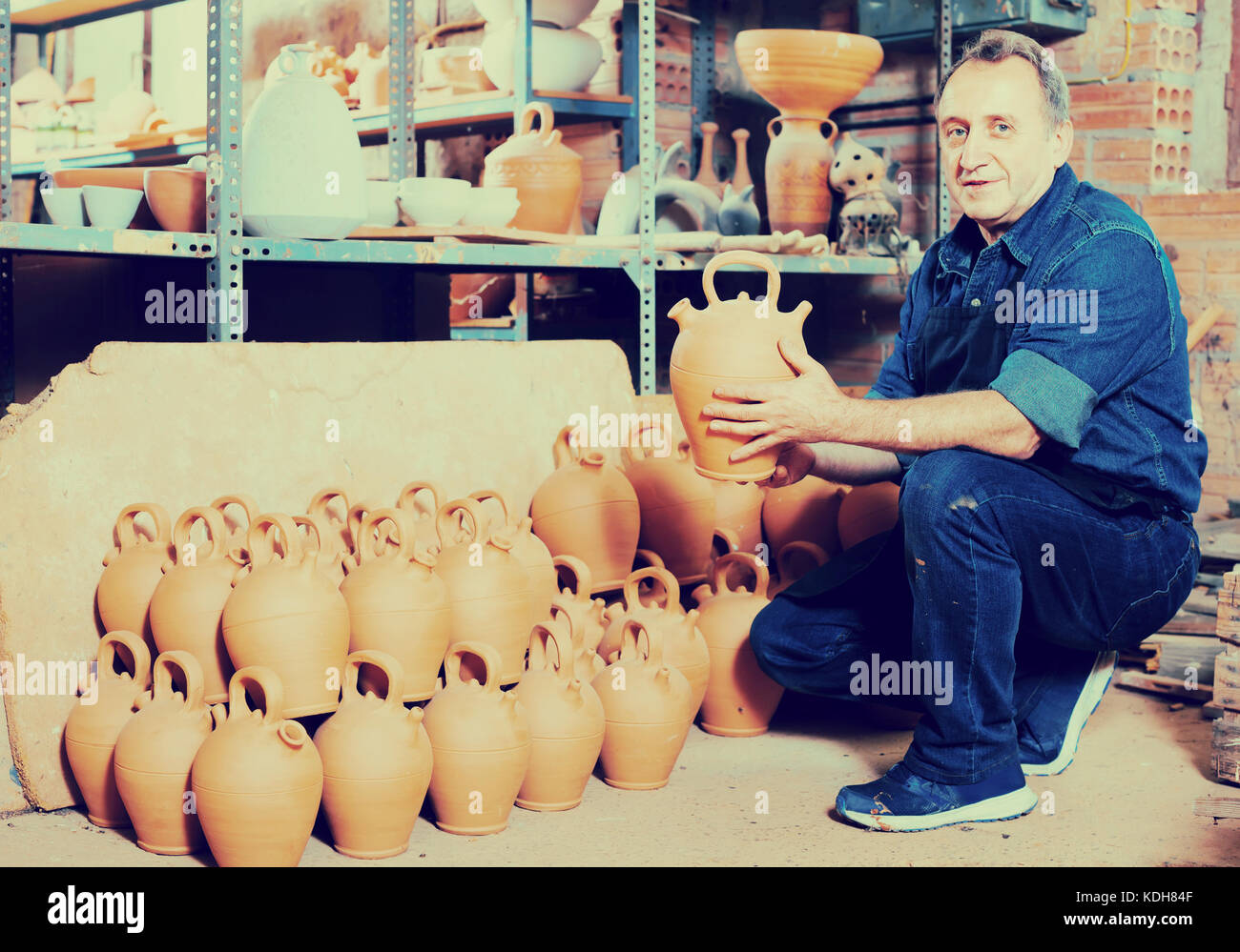Smiling elderly man holding pottery at ceramic workshop Stock Photo - Alamy
