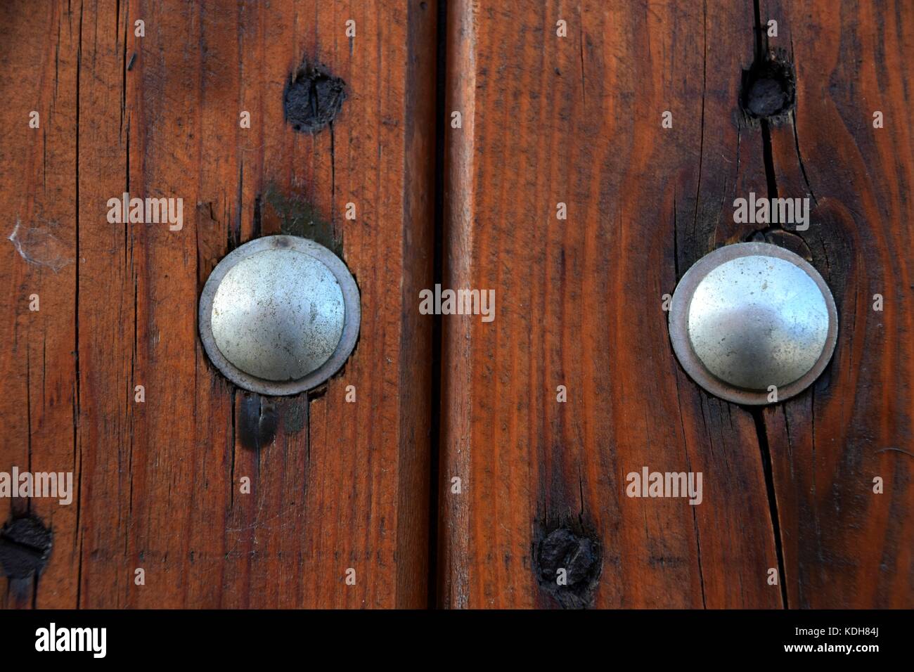 stainless steel metal bolts in wooden door, close-up of metal bolt with ...