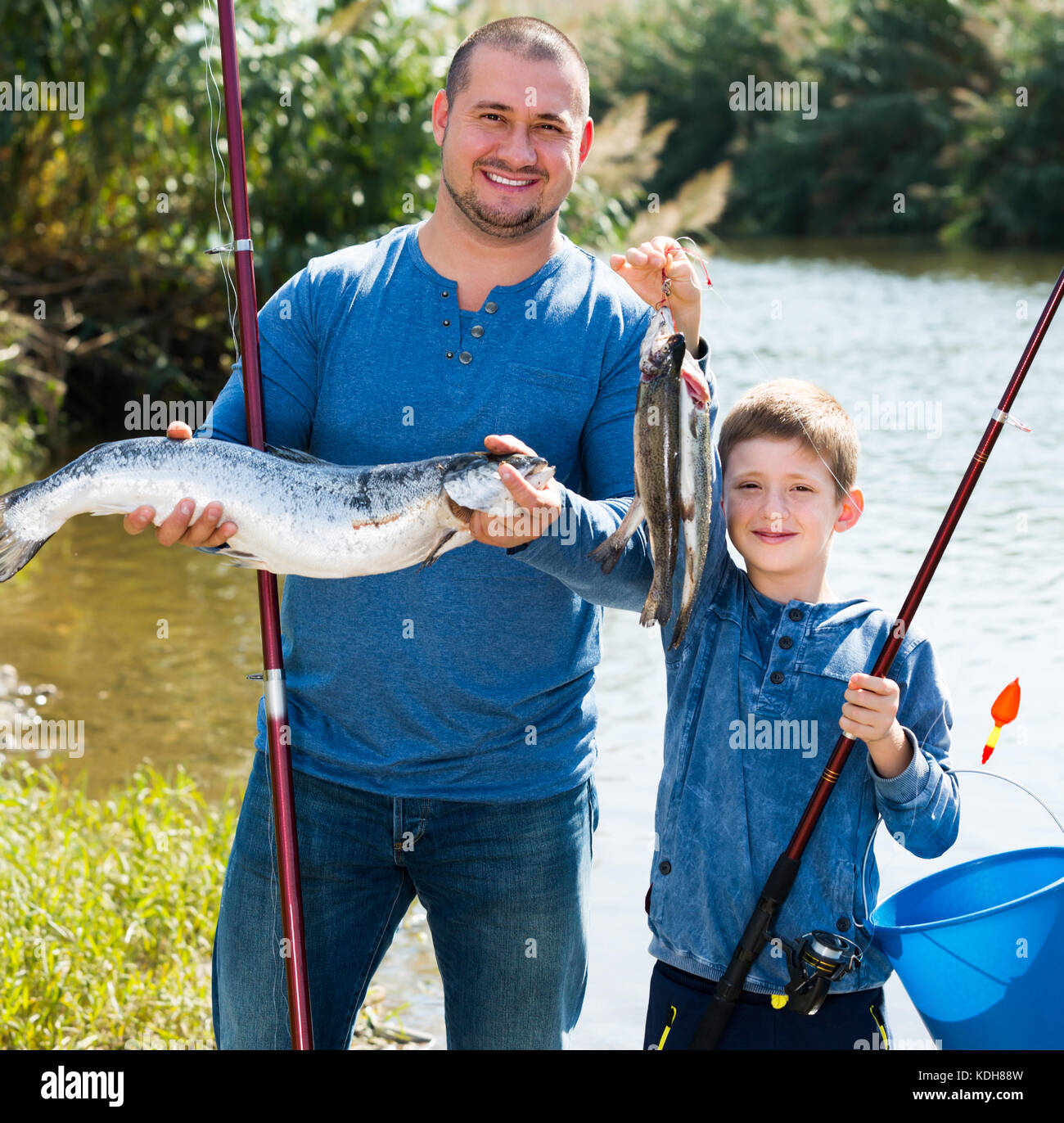 Smiling father and son fishing with rods in summer day Stock Photo - Alamy