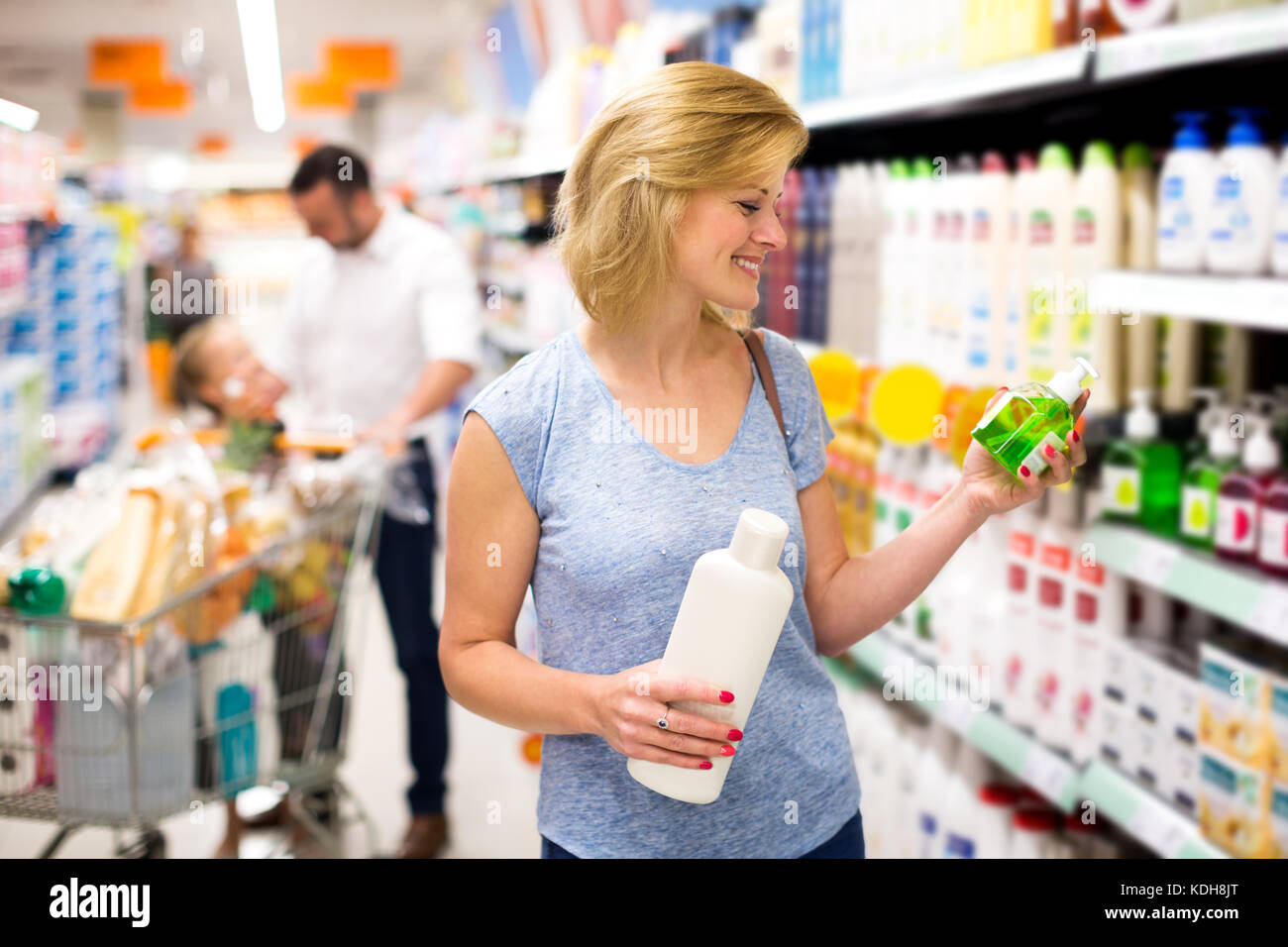 Attractive woman customer choosing shampoo in cosmetics department ...