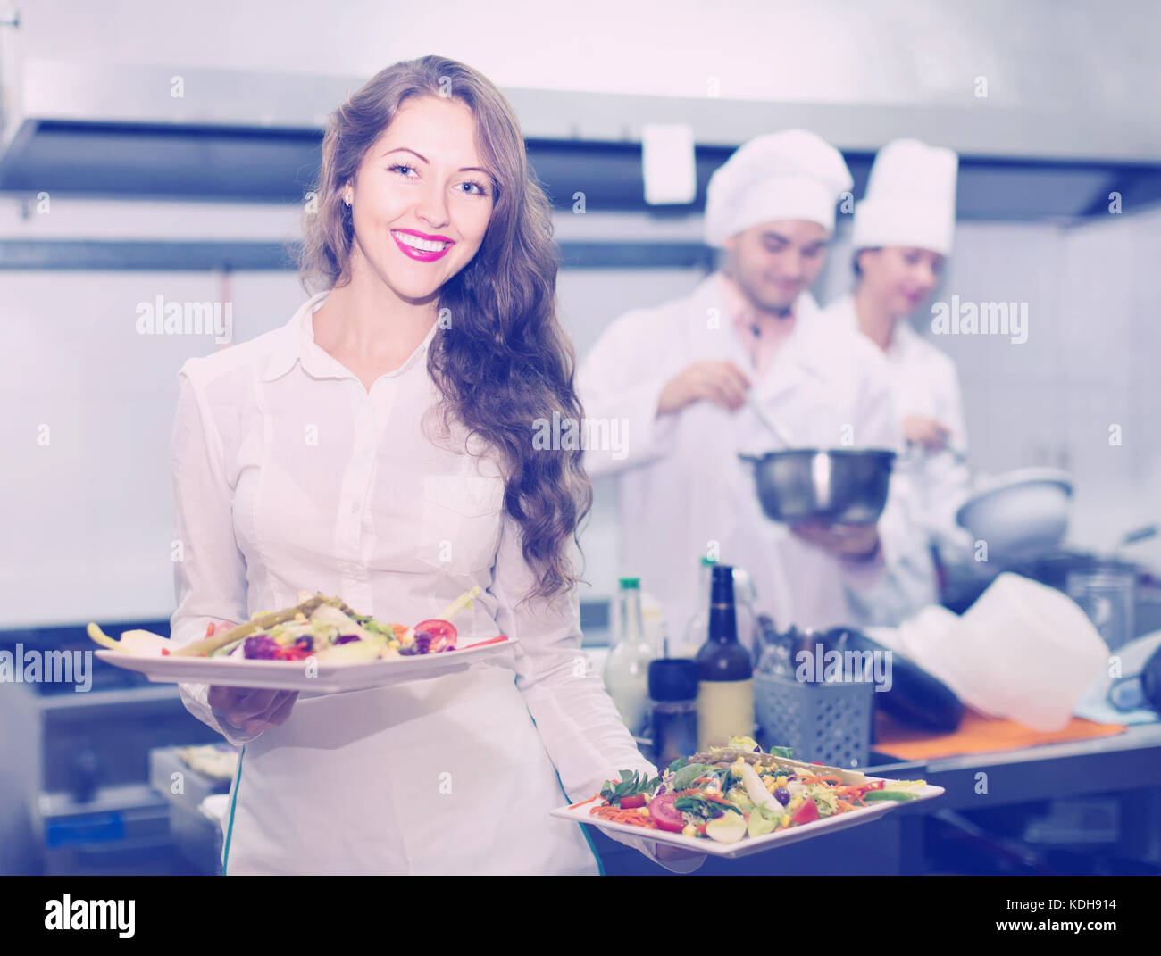 Beautiful smiling female waiter taking dish from kitchen in cafe Stock ...