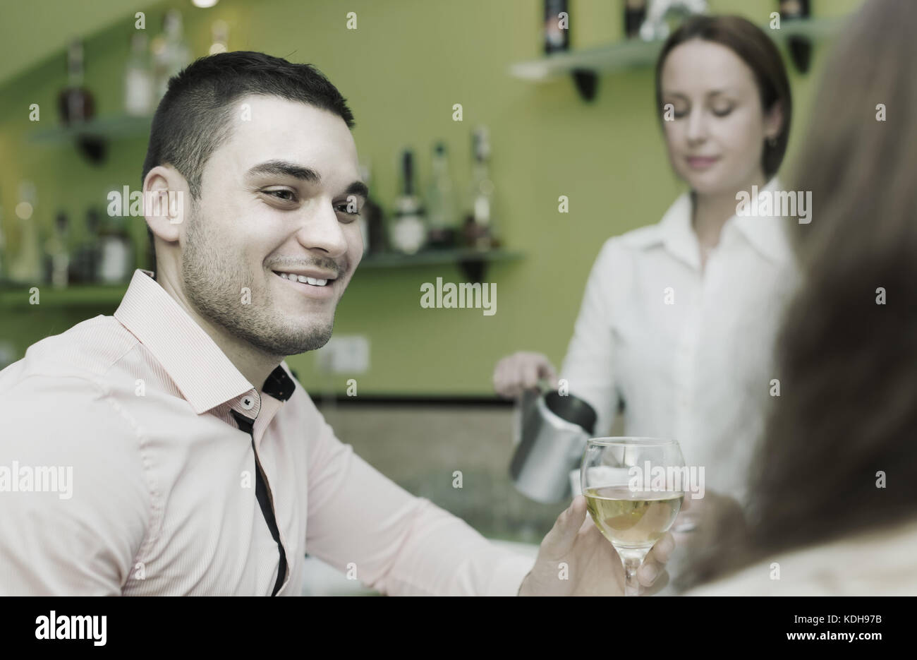 Small bar with female barista and two clients at counter. Focus on man ...