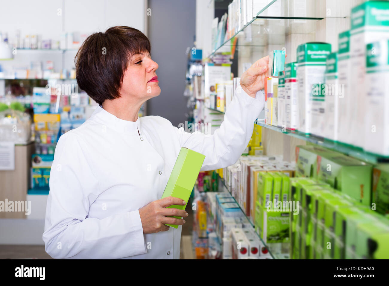 smiling woman pharmacist wearing uniform and working in pharmaceutical ...