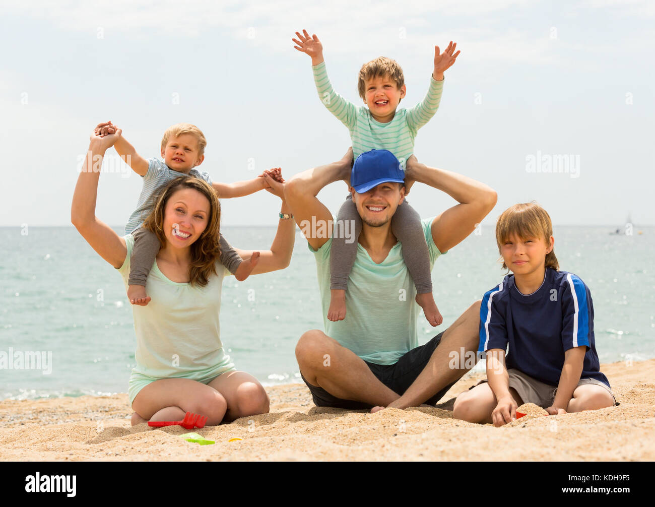 Positive parents with three children on beach in vacation at seaside ...