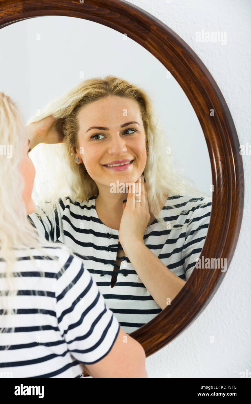 Young woman looking in mirror after waking up Stock Photo - Alamy