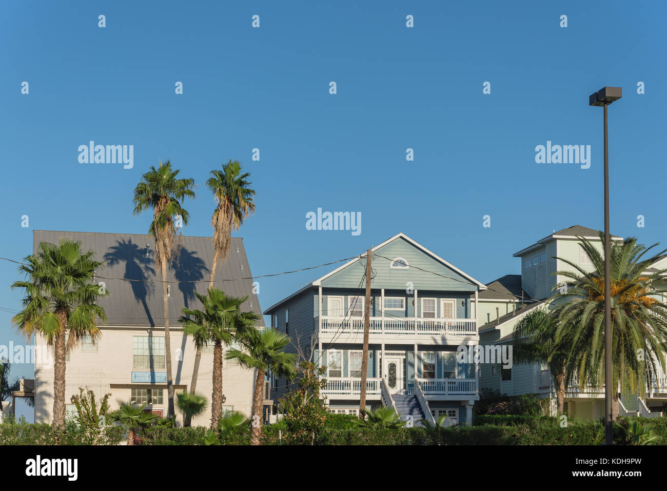 Rear view of three-story waterfront vacation home with palm trees in ...