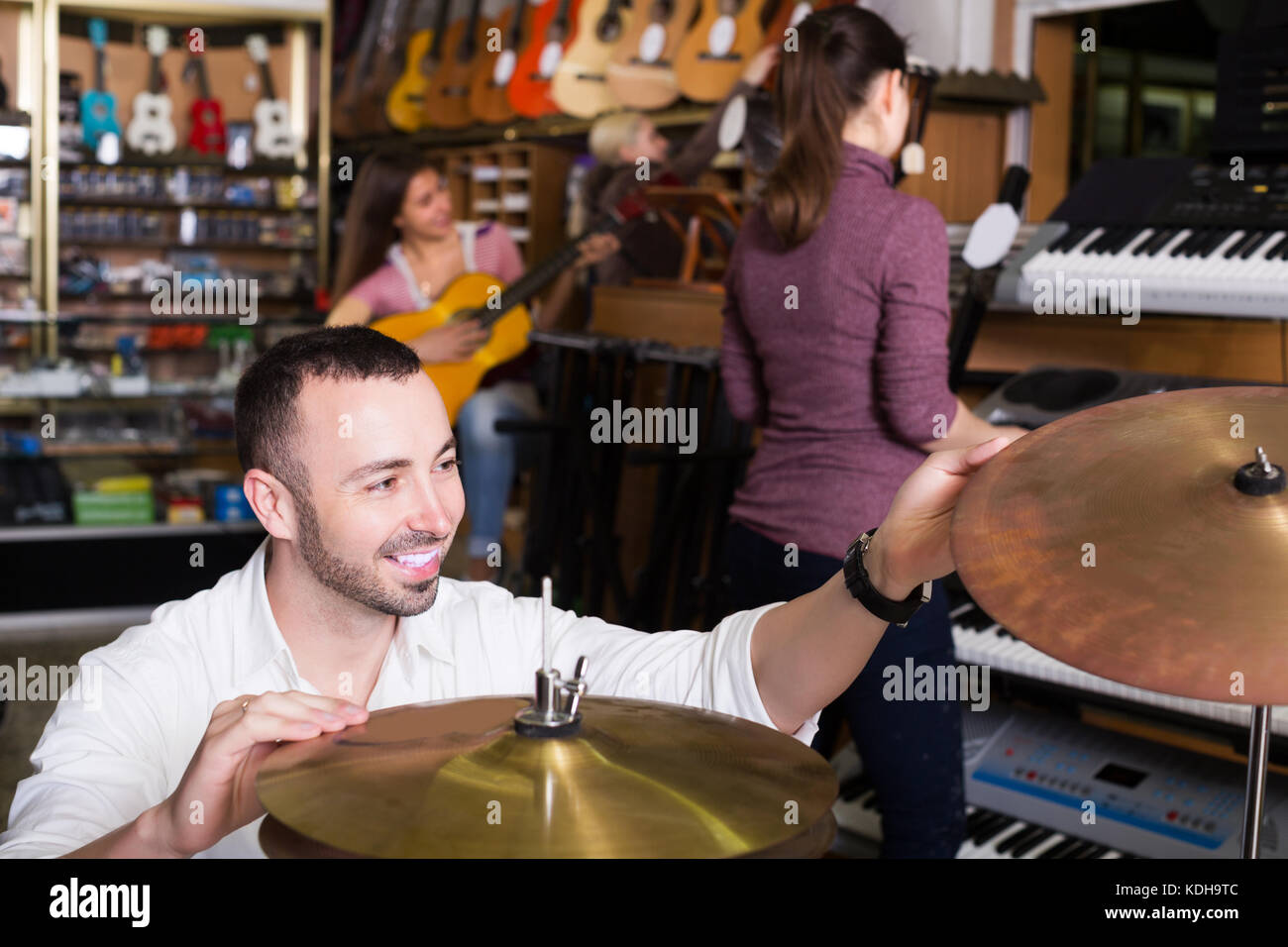 Different people looking at professional musical instruments in store ...