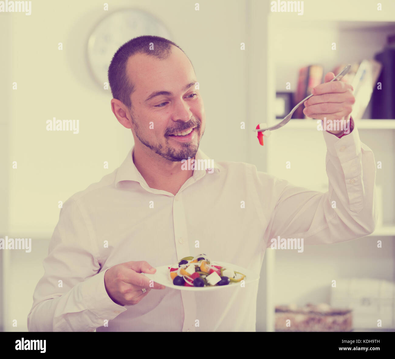 Positive young man ready to eat greek salad in office Stock Photo - Alamy